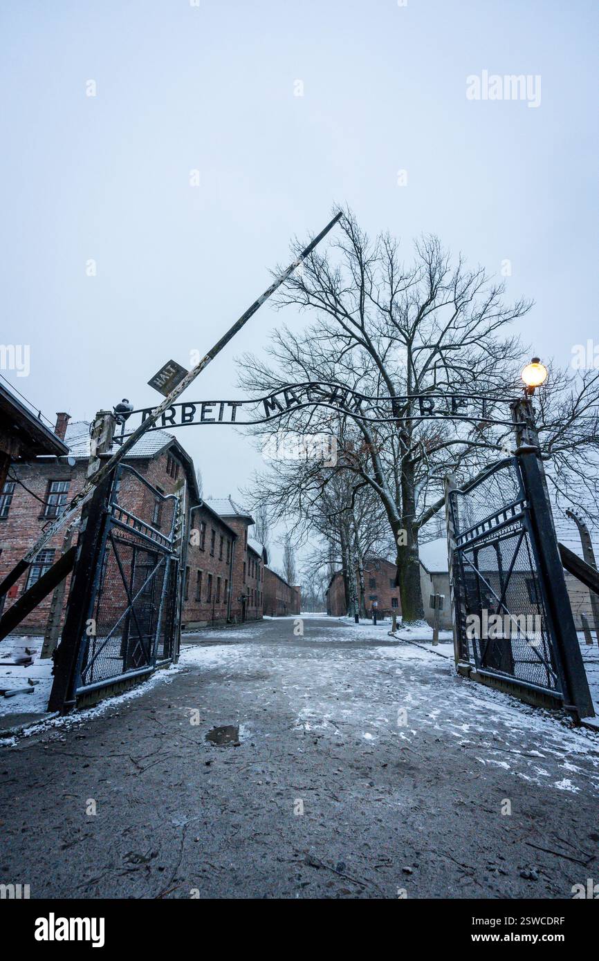 Entrance gate of Auschwitz on a snowy evening with streetlights glowing ...