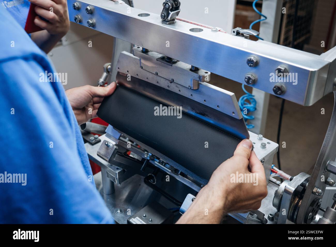 Worker manipulating a black object within industrial equipment Metal ...