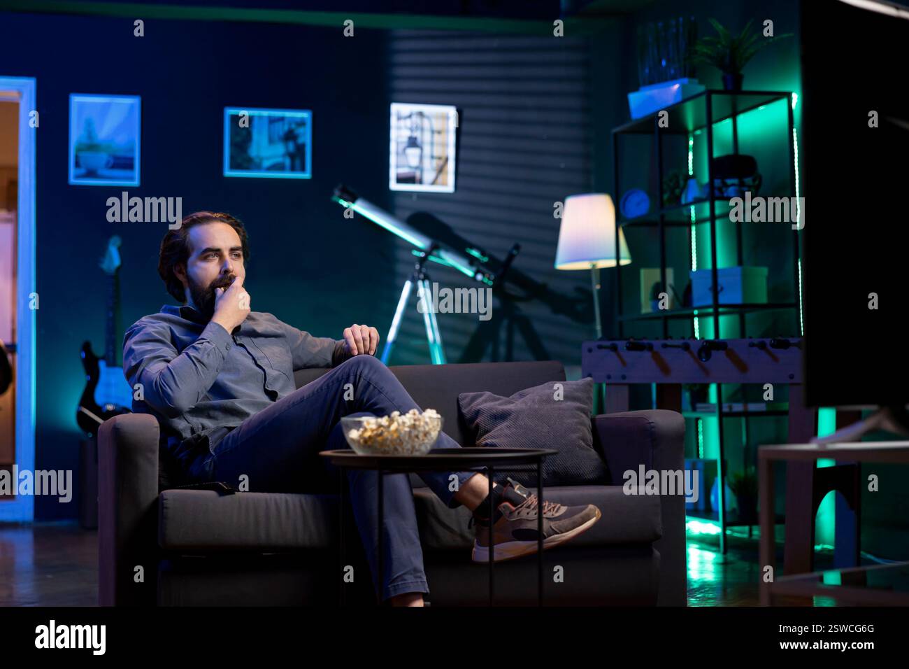 Cord cutter sitting on couch eating popcorn in front of TV displaying ...