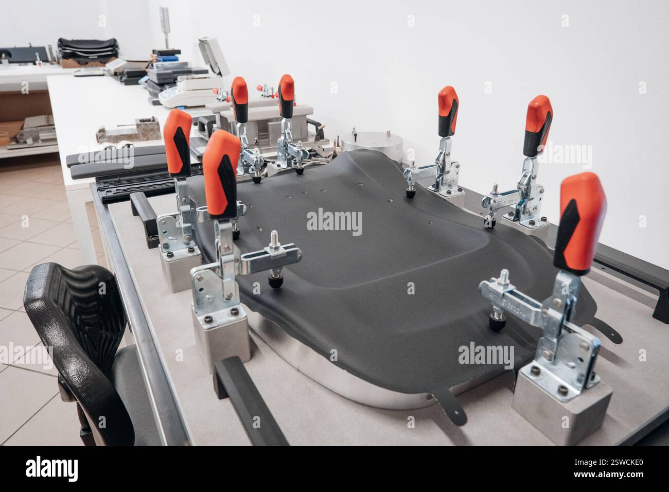 Manufacturing process showcasing quality control with a gray automotive component being clamped ...