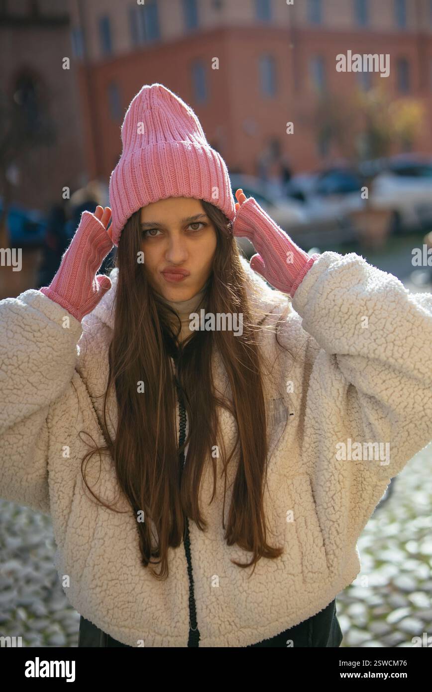 A stylish young woman striking a pose outdoors in cozy winterwear ...