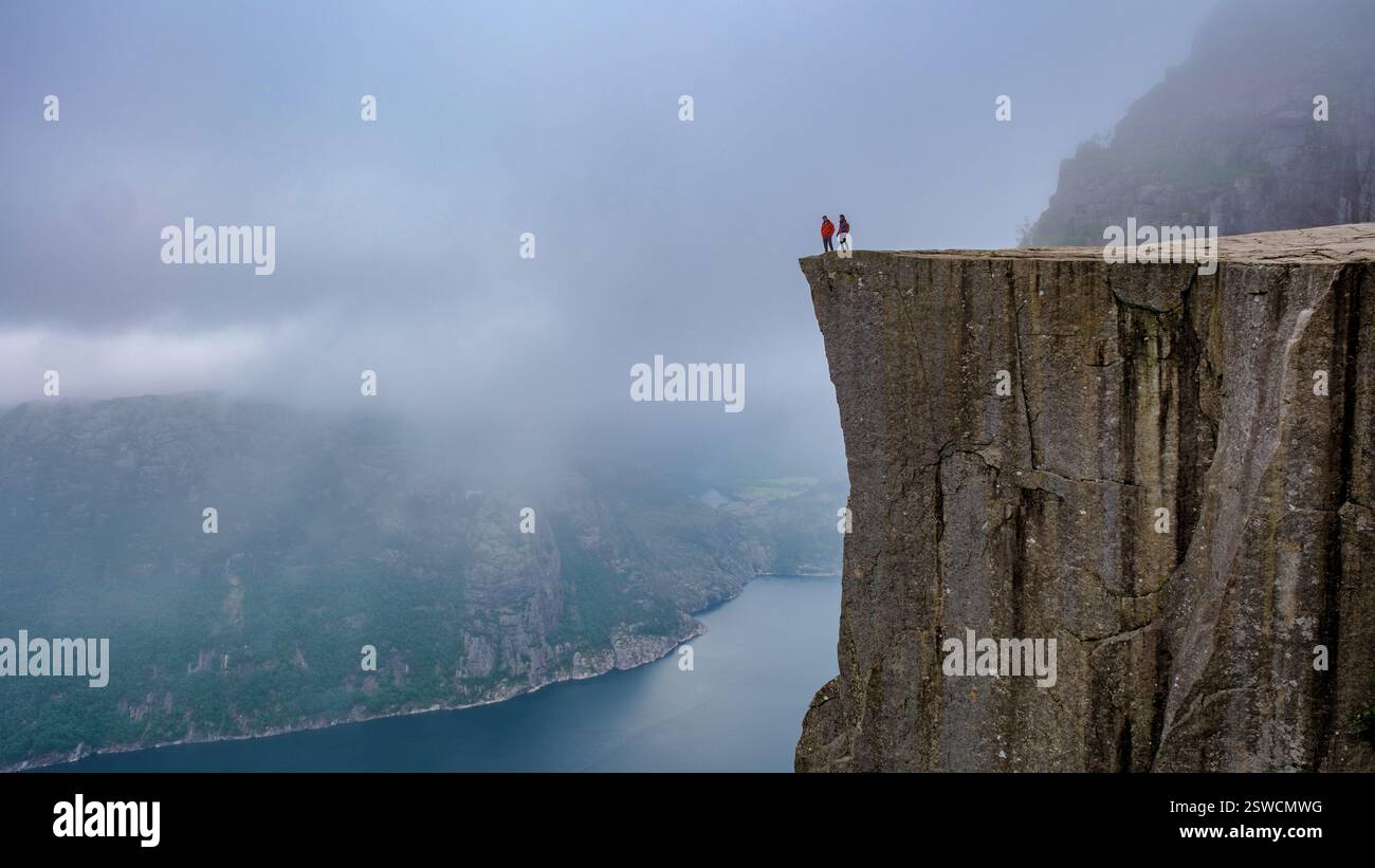 Preikestolen, Norway, A hiker stands on the edge of a cliff with arms ...