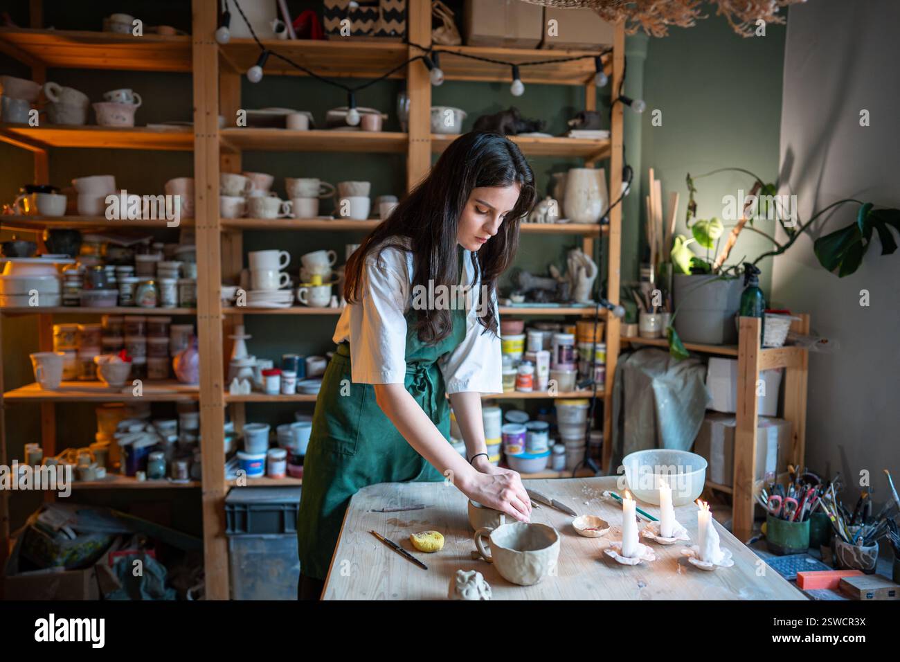 Woman learning how to make hand-formed tableware during pottery ...