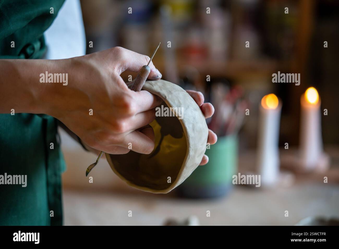 Female hands of potter shape bowl from white clay in pottery workshop. Pottery skills, manual ...