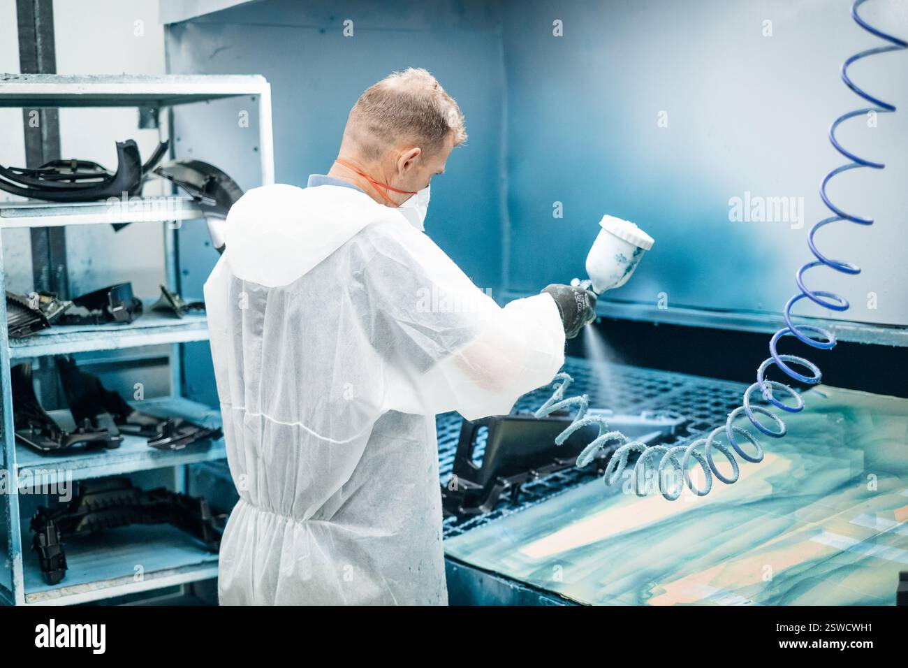 Protective gear worker using spray gun in a painting booth Automotive ...