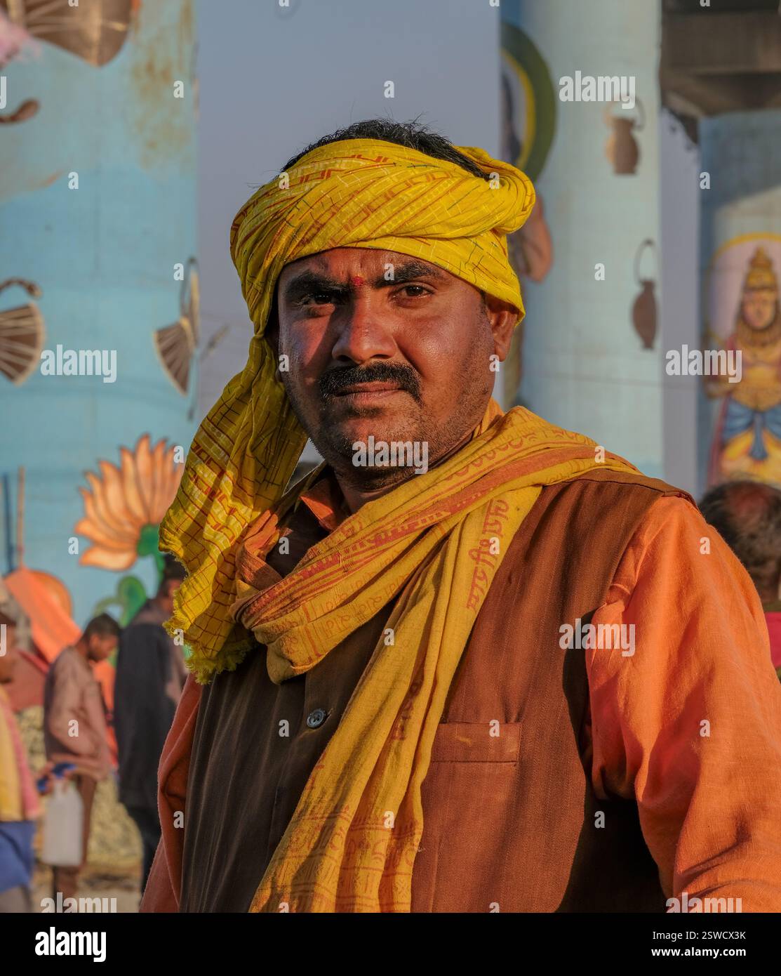 A portrait of a man during the Kumbh Mela, wearing a yellow turban and ...