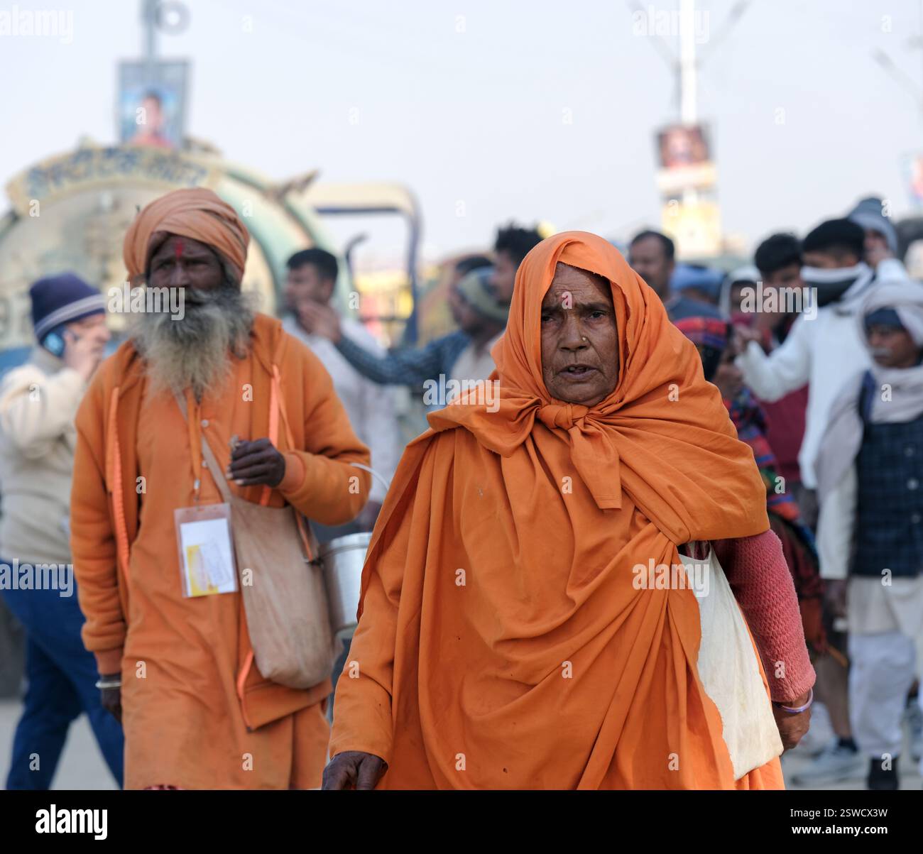 Two elderly pilgrims in traditional attire walk through the vibrant ...