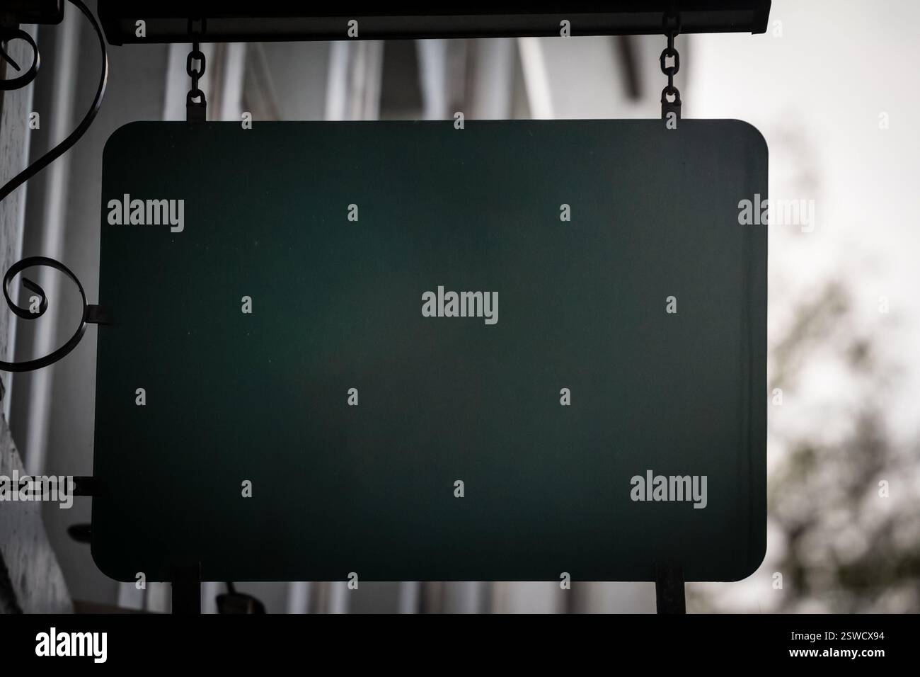 An empty horizontal green rectangular sign hanging on the exterior of a ...