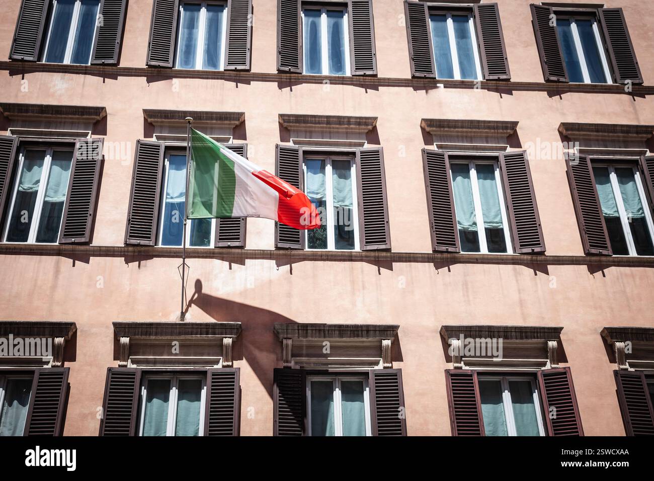 An Italian flag waves from a pastel facade with classic shutters ...