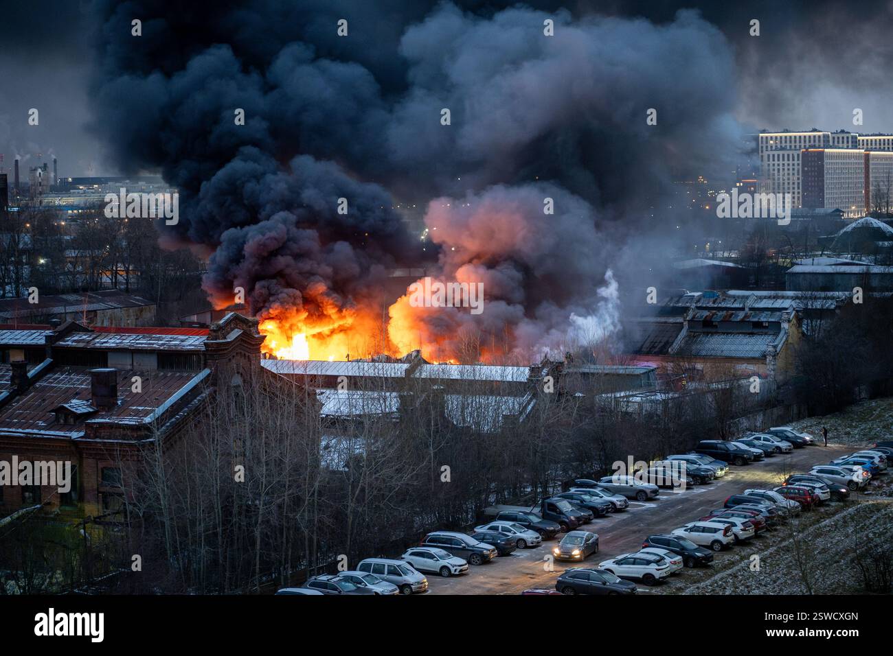 Blackened house burning on outskirts of city, smoke rising high into sky in residential city ...
