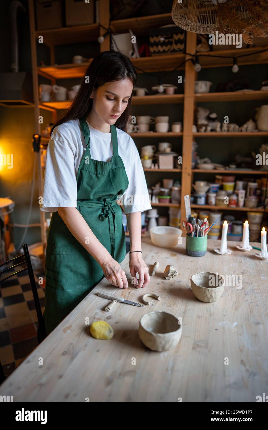 Woman ceramist make pottery cup handle in studio. Creative girl pottery ...