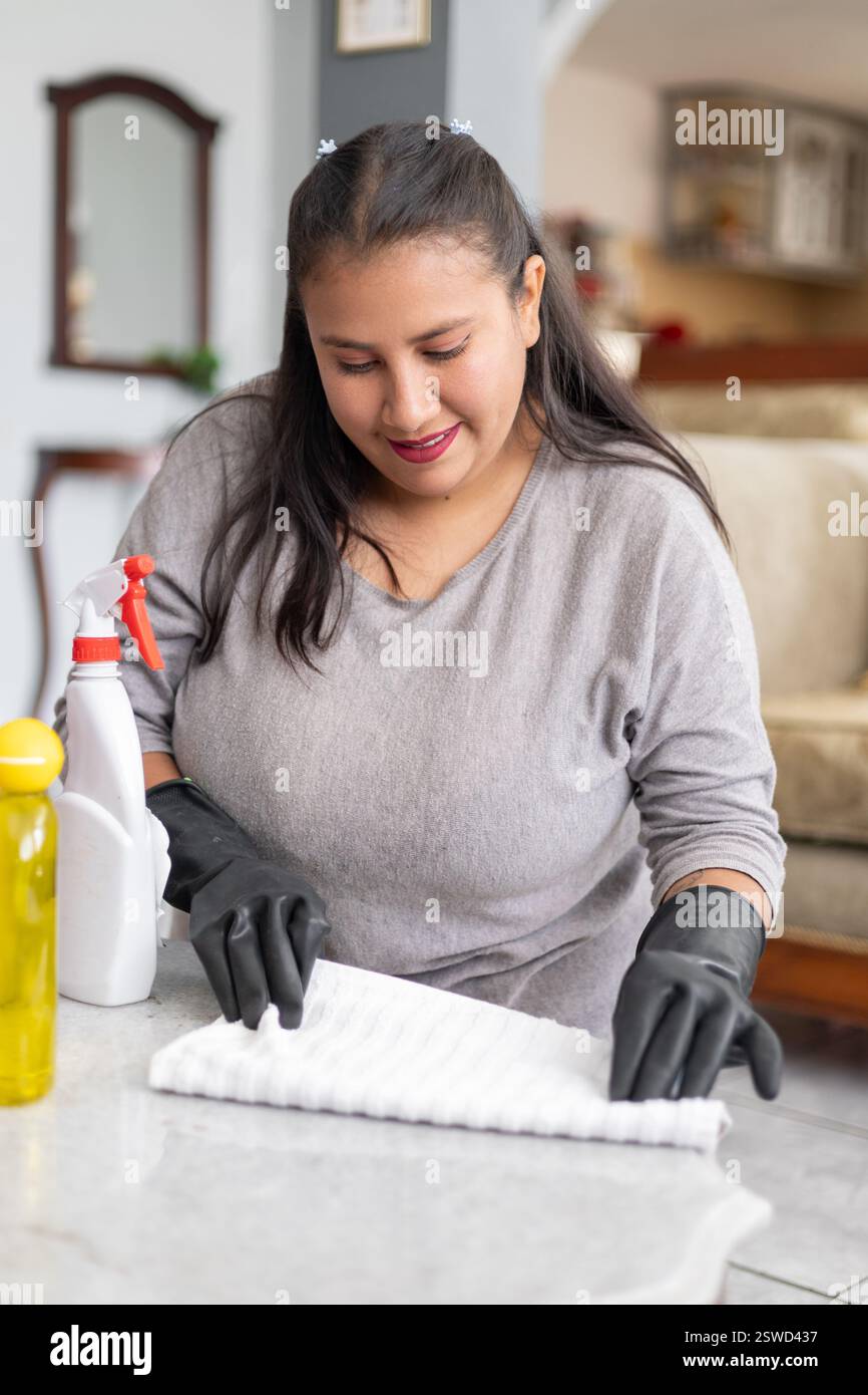 A domestic worker carefully cleans the dining table, ensuring every ...