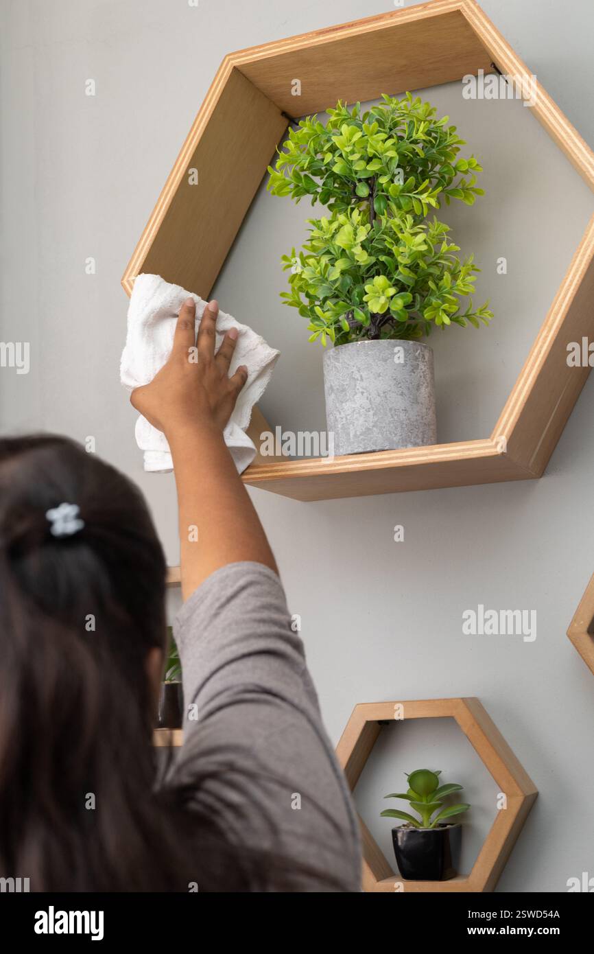 A wife carefully cleans the shelves in her home, organizing and dusting ...