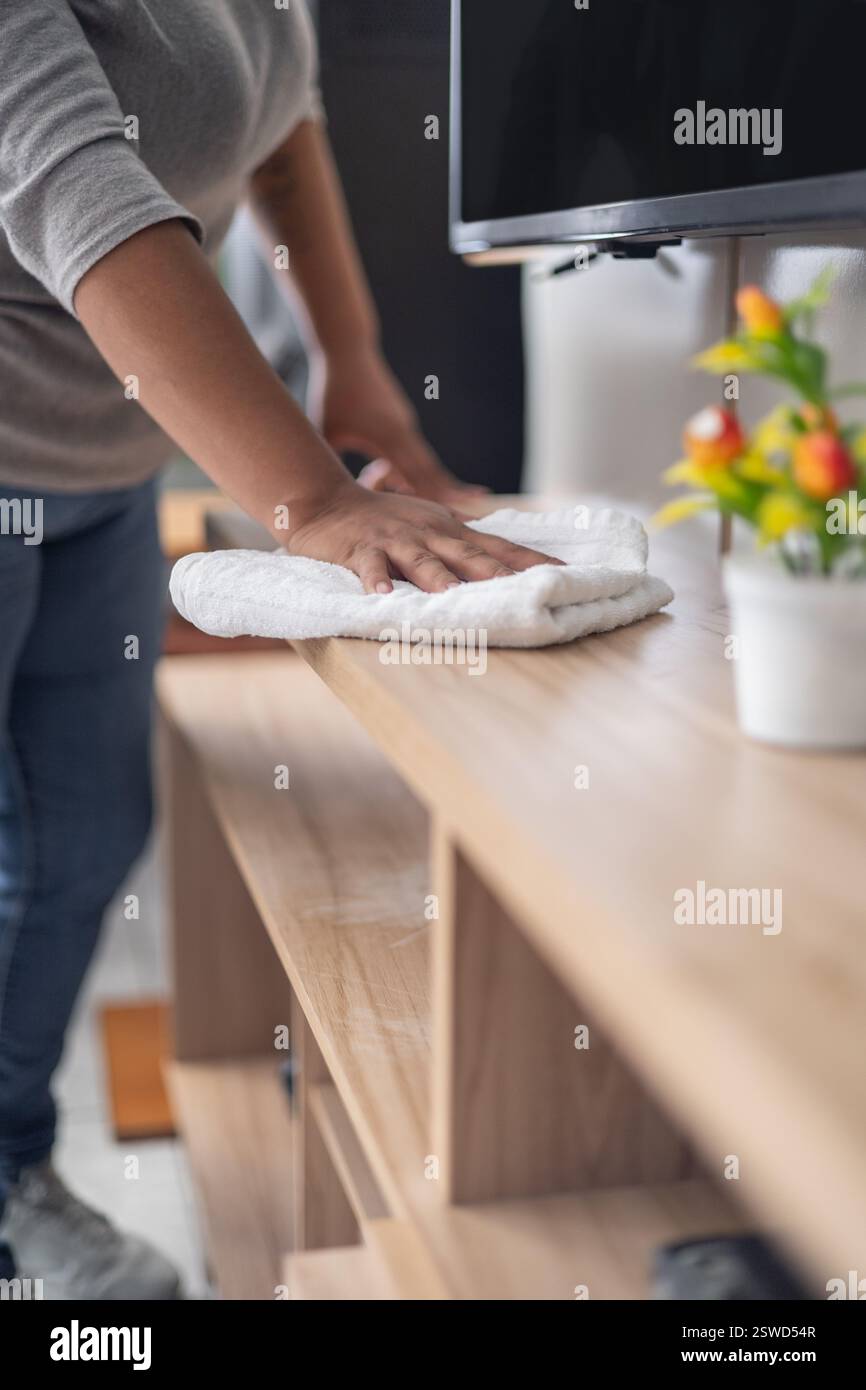 A woman's hands using a cloth to clean a TV stand, perfect for home ...
