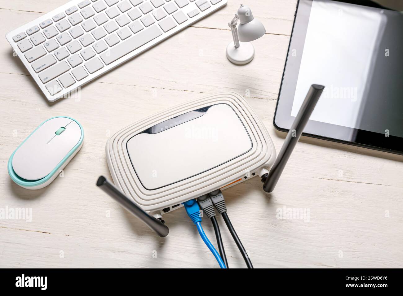 Modern wi-fi router with keyboard and tablet computer on white wooden ...