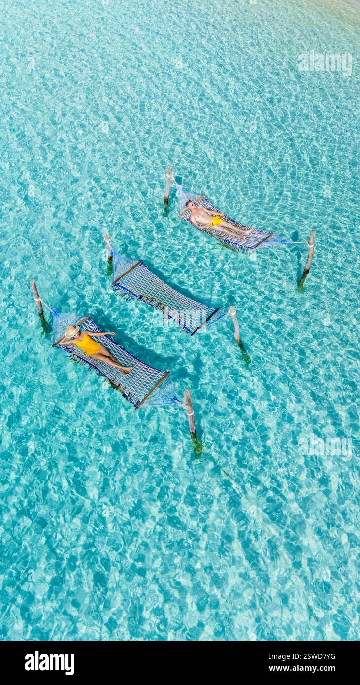 Three inviting hammocks rest on stilts above the turquoise waters of ...