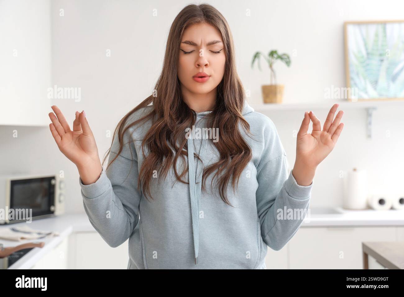 Young woman trying to calm down while having panic attack in kitchen ...