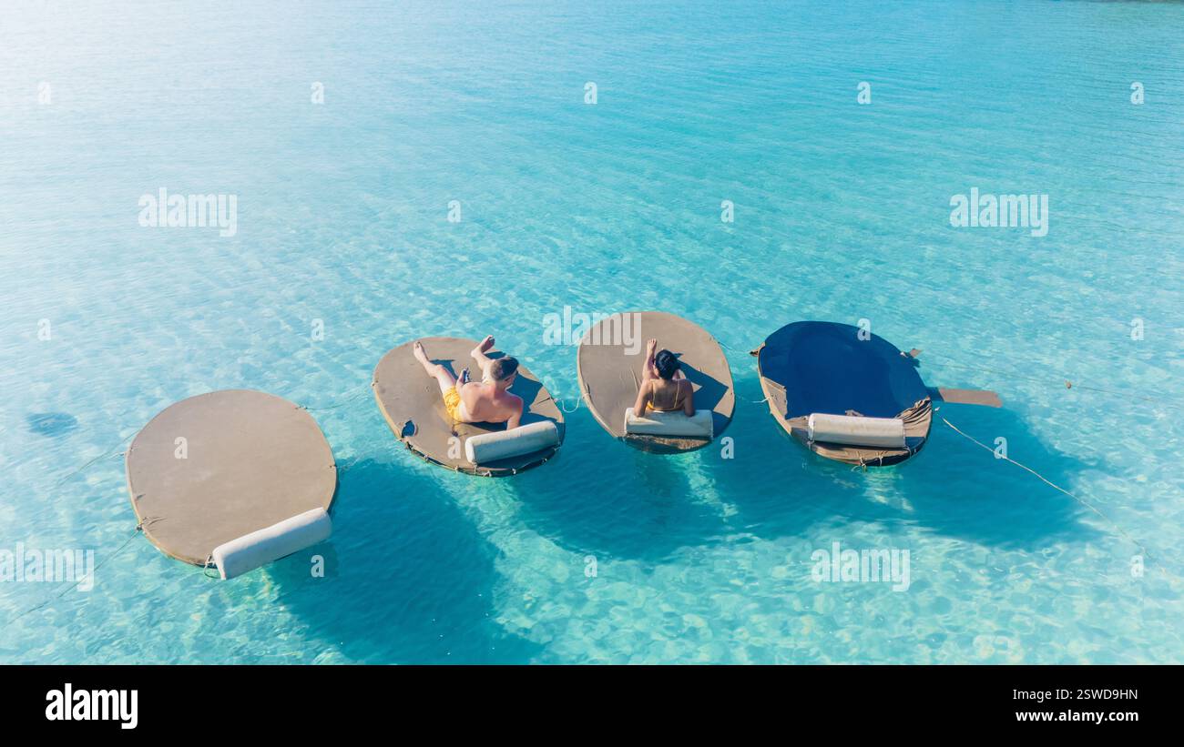 Float away in serene bliss as two sunbathers lounge on serene platforms ...