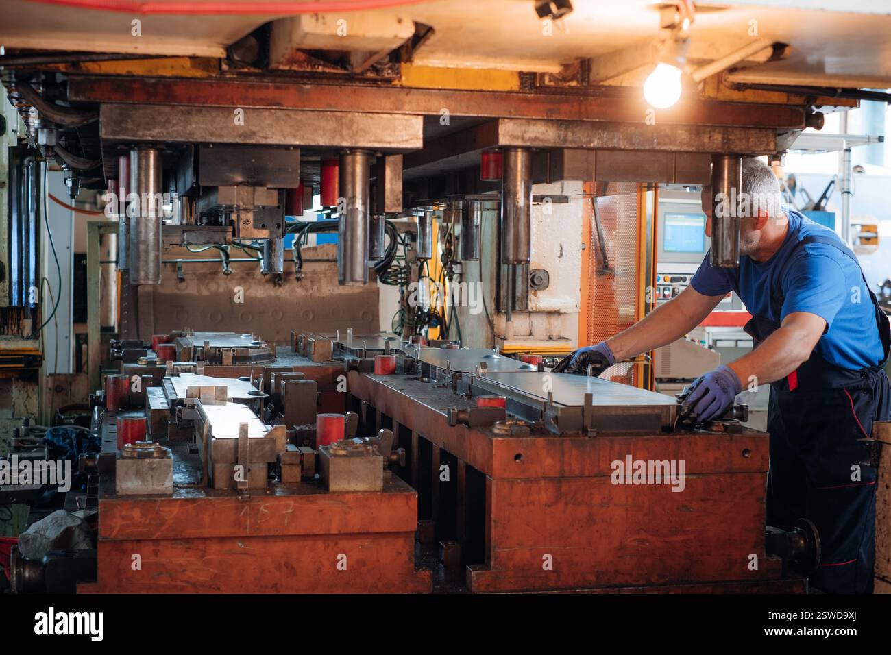 Worker using heavy industrial machinery metal forming process ...