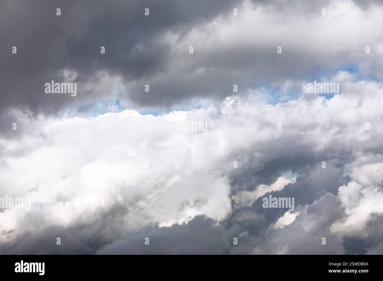 Vast expanse of cumulus clouds, showcasing a mix of light and shadow. Layers of puffy white and ...