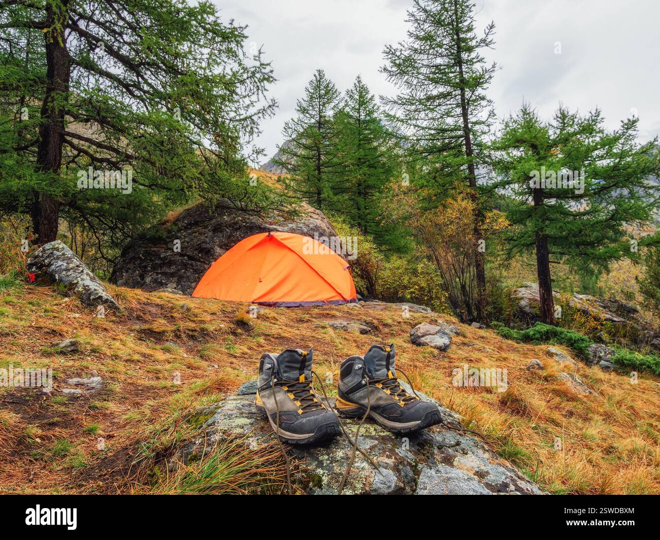 Wet hiking boots to dry. Atmospheric mountain landscape with tent under ...