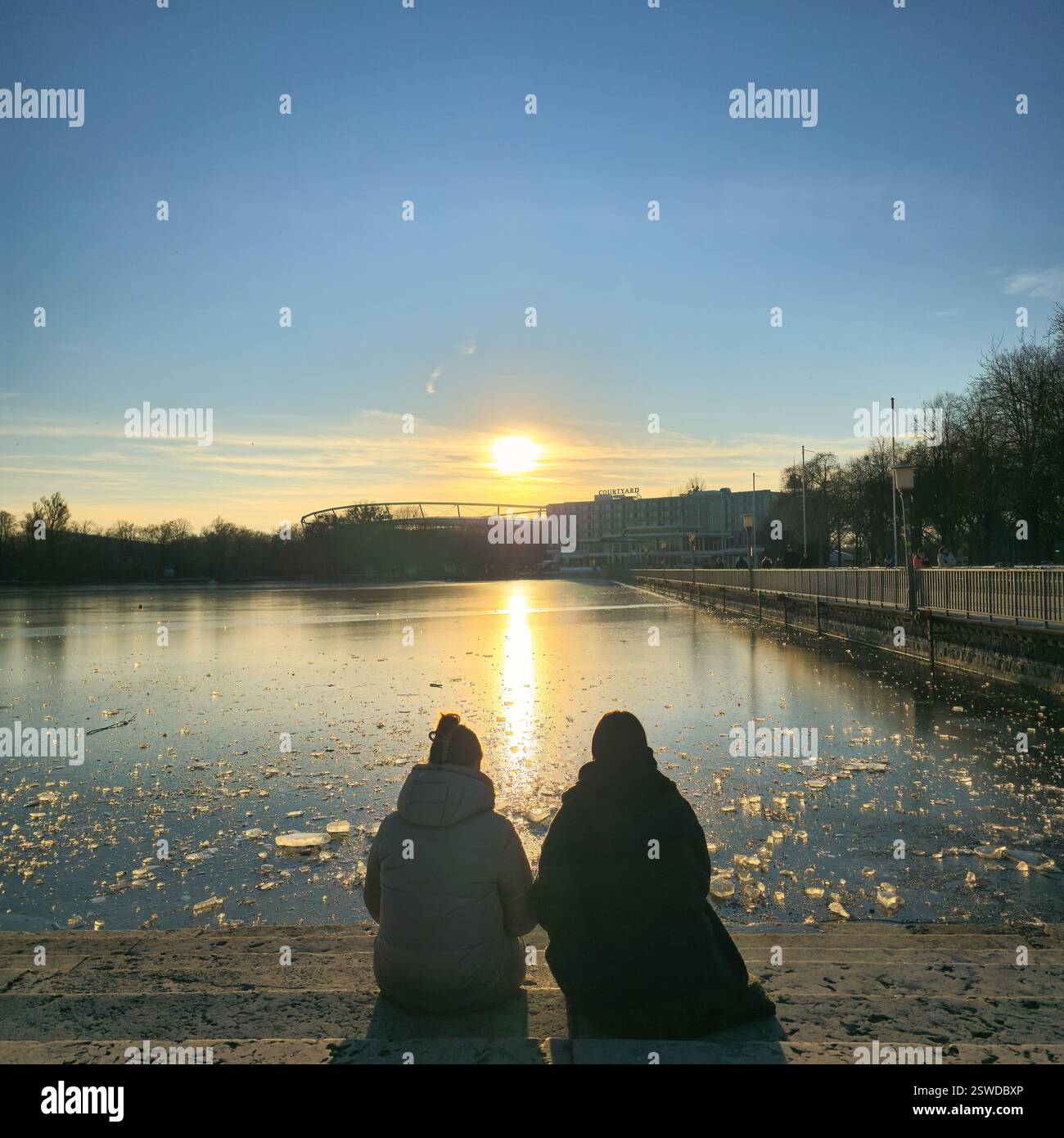 Two close friends sit by the iced water, enjoying a tranquil sunset ...