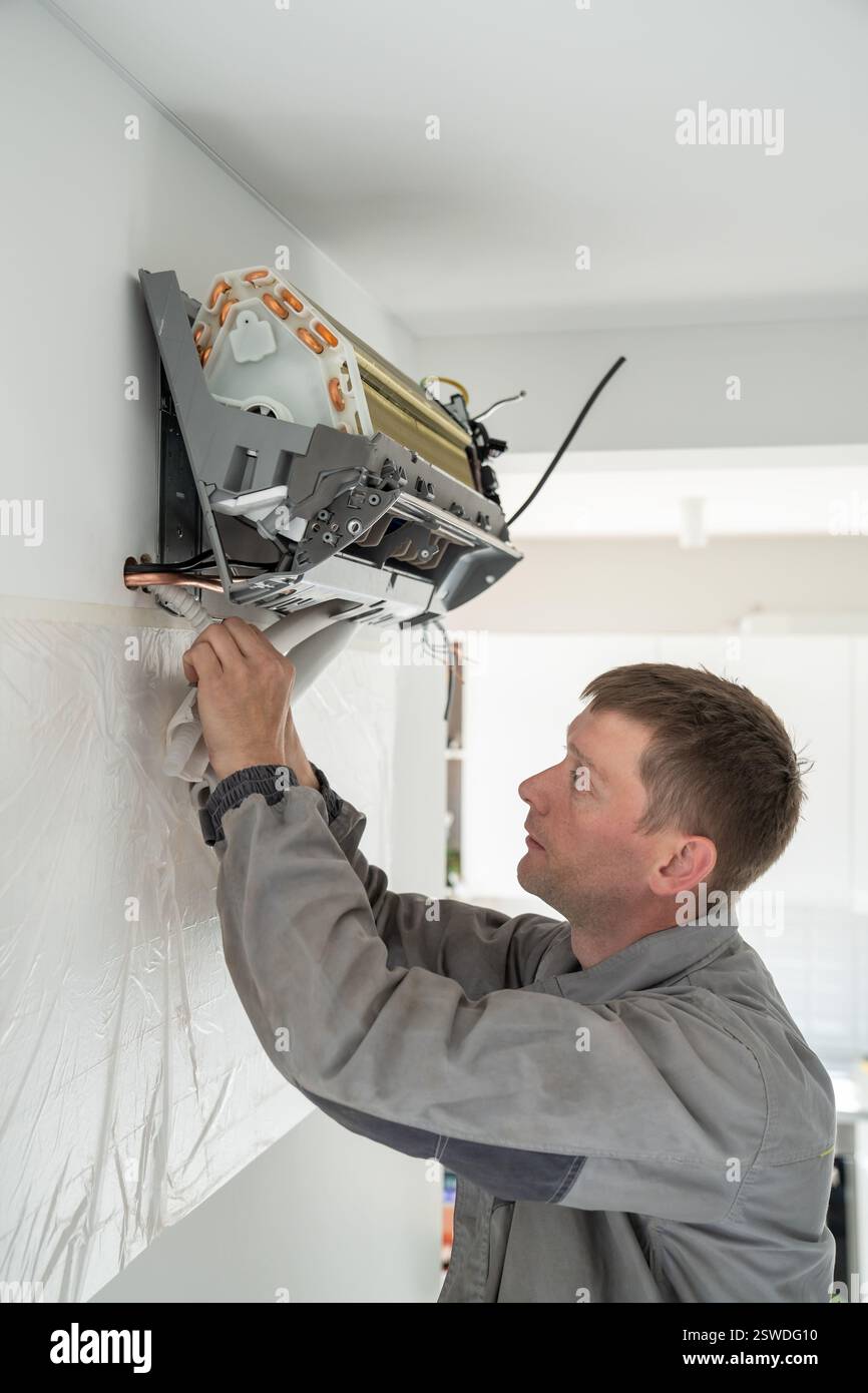 Installing air conditioner in apartment. Technician man in work uniform ...