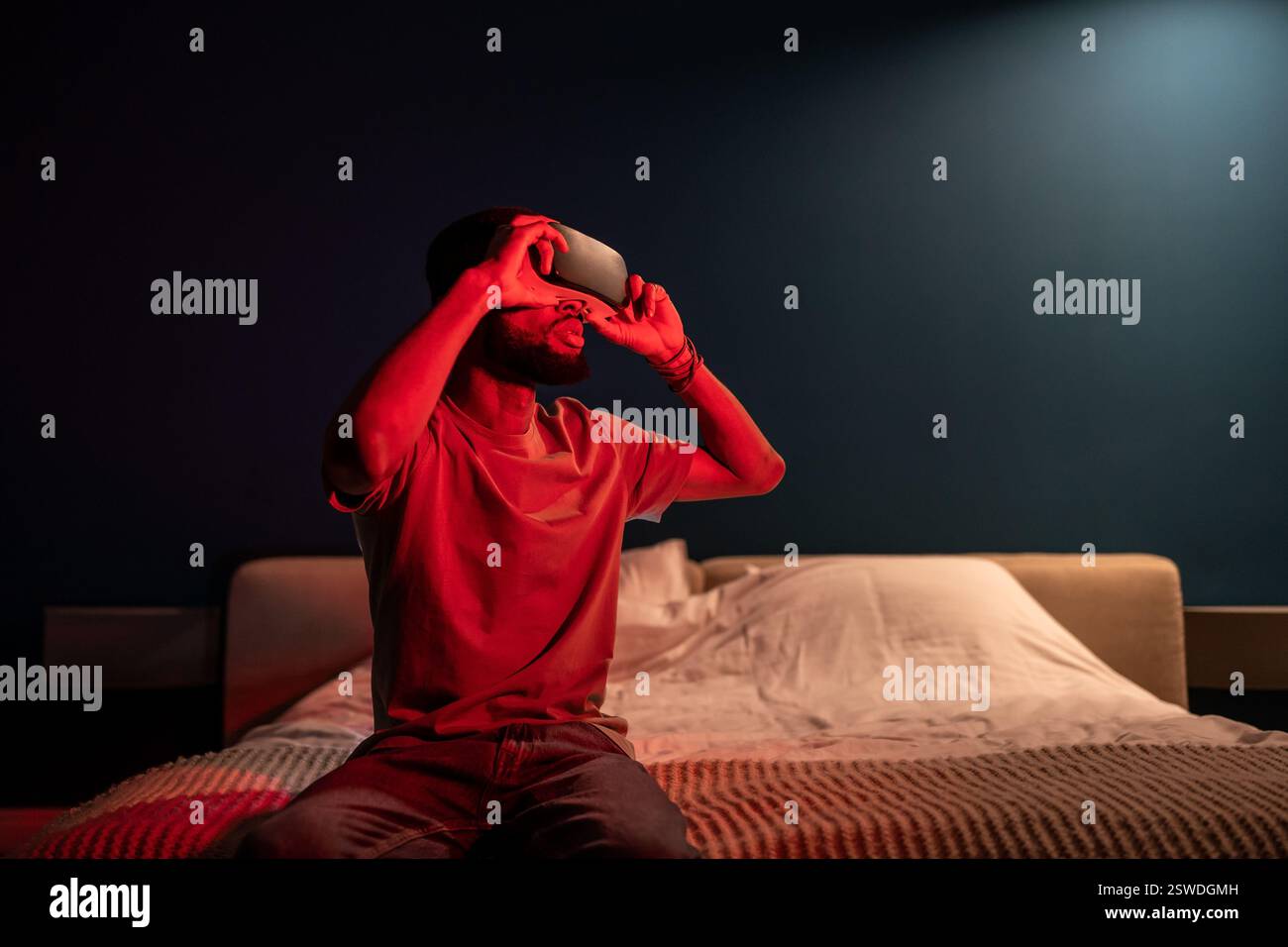 African man wearing VR glasses fully immersed in virtual world, sitting ...