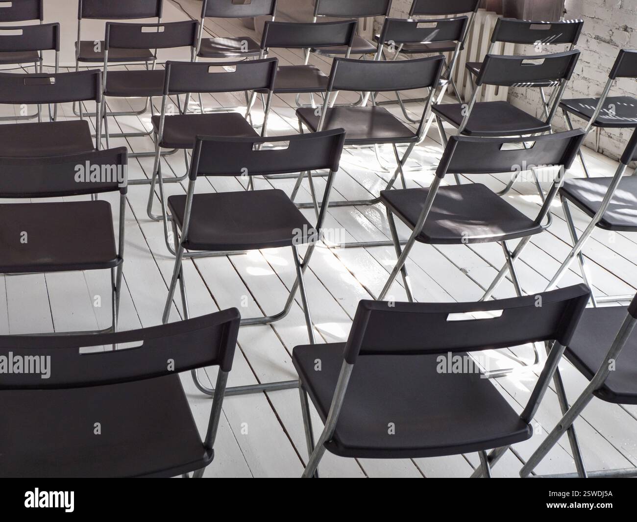Black folding chairs stand in rows in the white conference room Stock ...