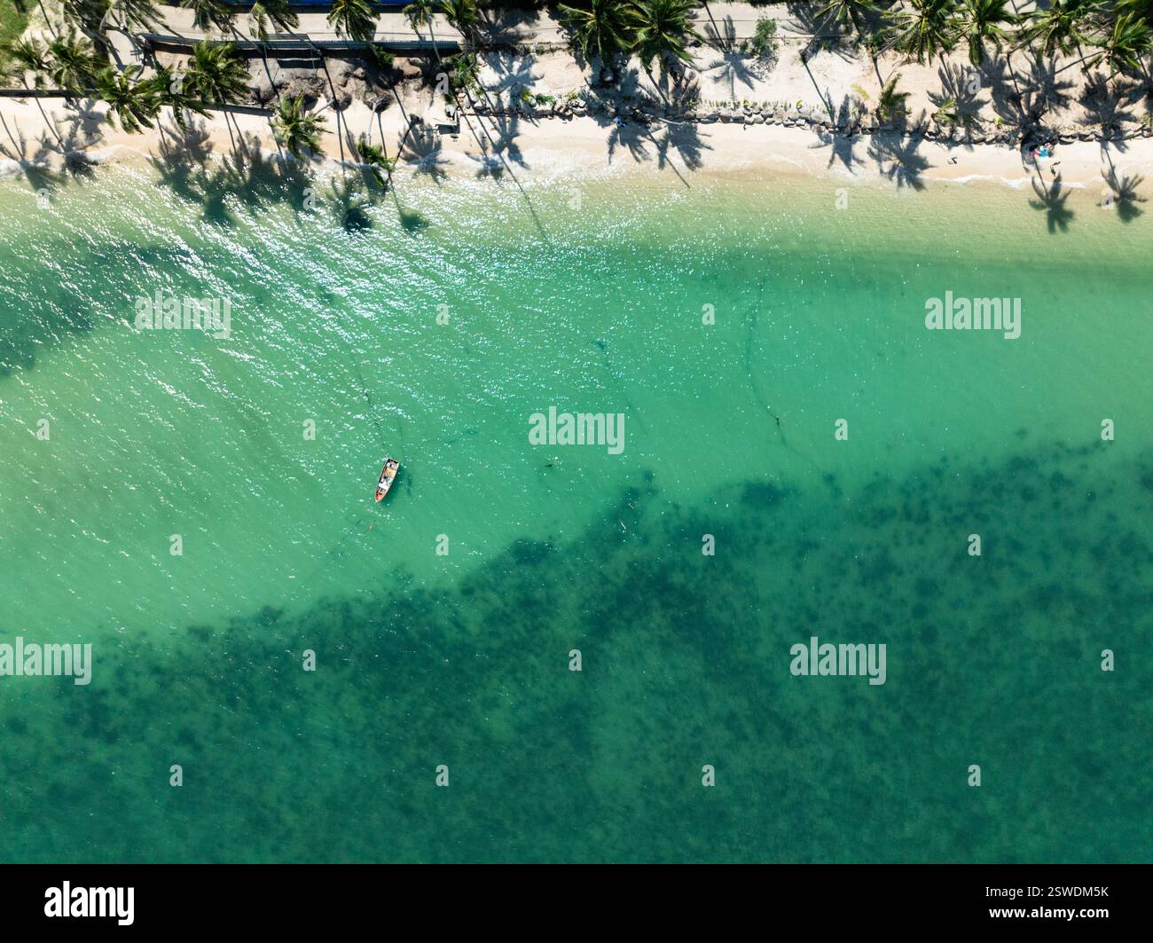Emerald green water with visible seabed and a small fishing boat near ...