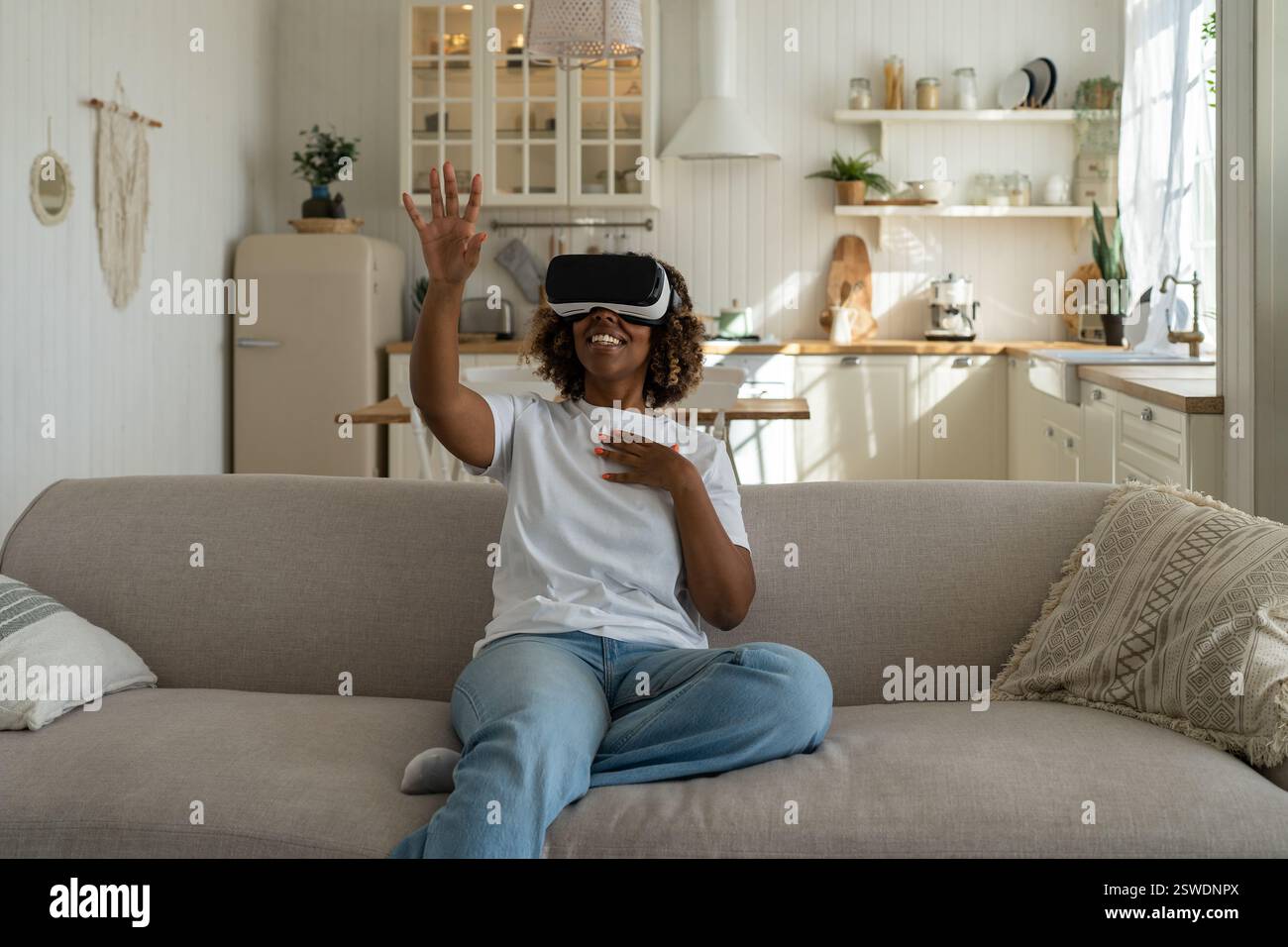 Young woman in VR headset touches air duringvirtual reality experience ...