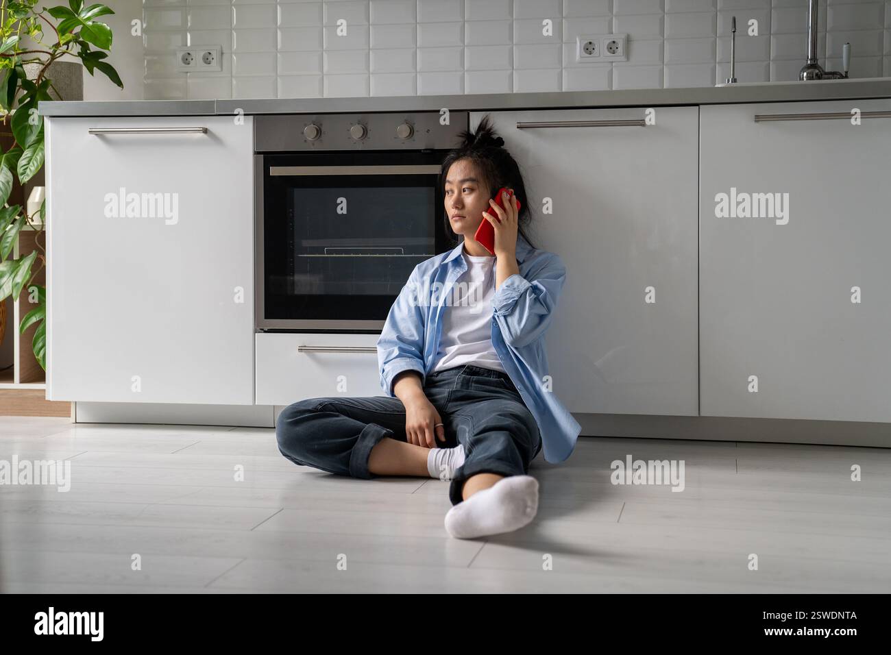 Asian woman sits on floor trying to solve problem making phone call to ...