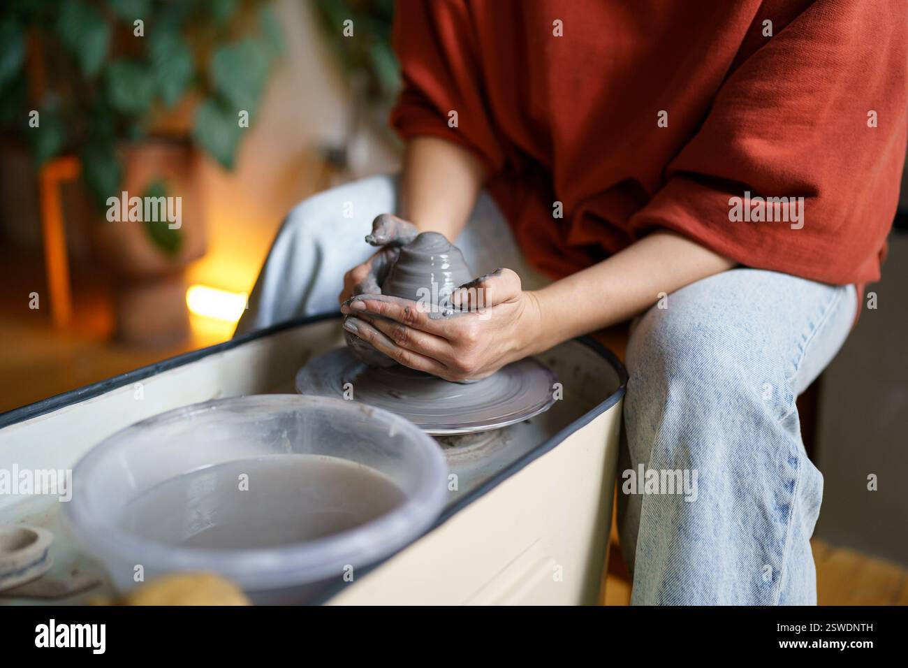 Female ceramist shaping walls of vase on rotating pottery wheel ...