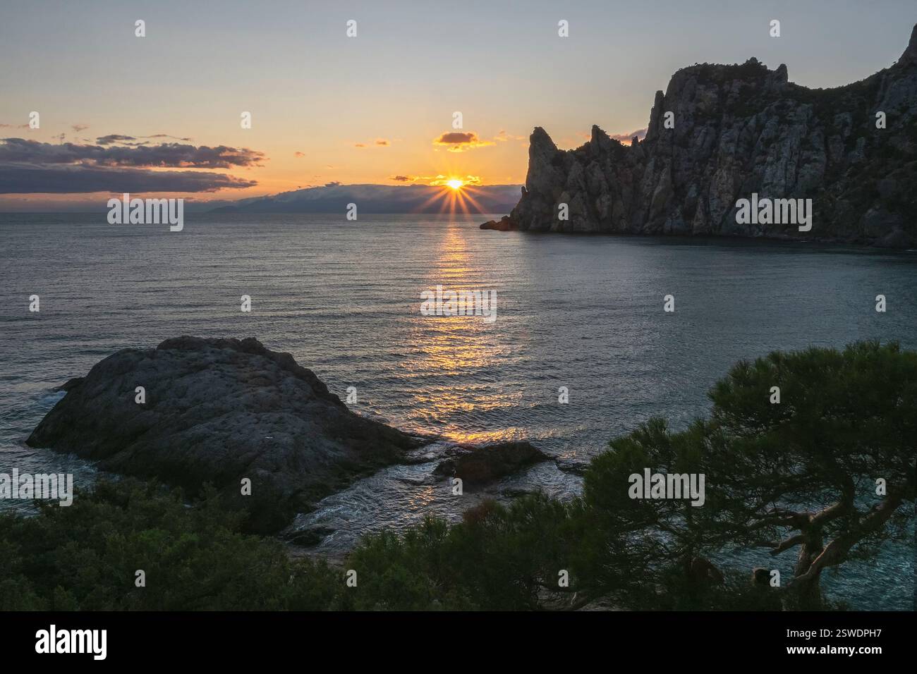 Last rays of the setting sun on the horizon near a cliff Stock Photo ...