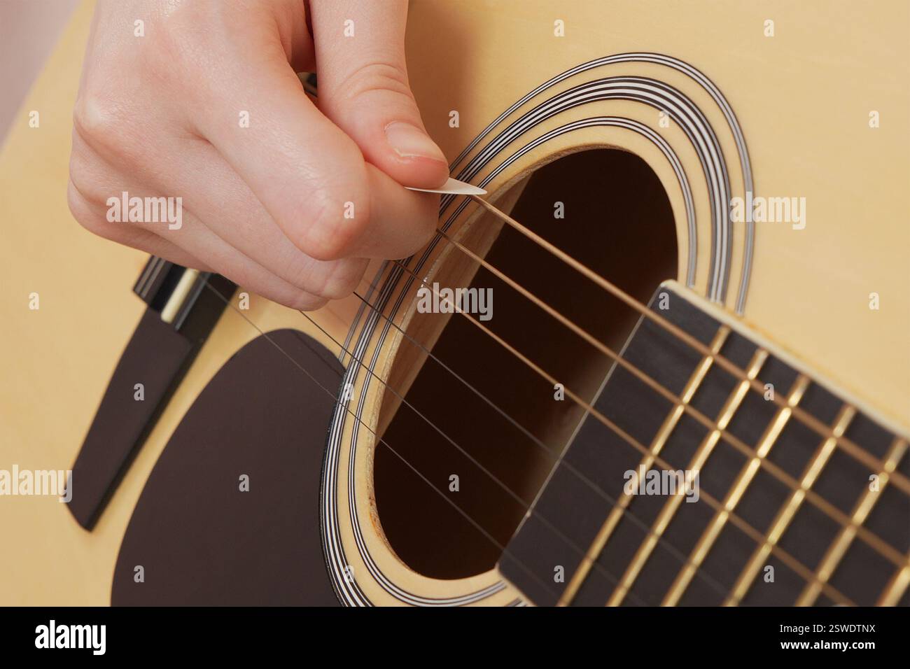 Extreme closeup of woman's fingers deftly handling guitar pick as she strumming six string ...
