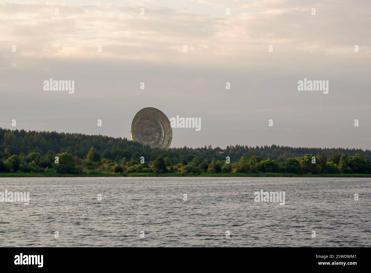 A huge satellite dish above the forest on the river bank. Radio ...