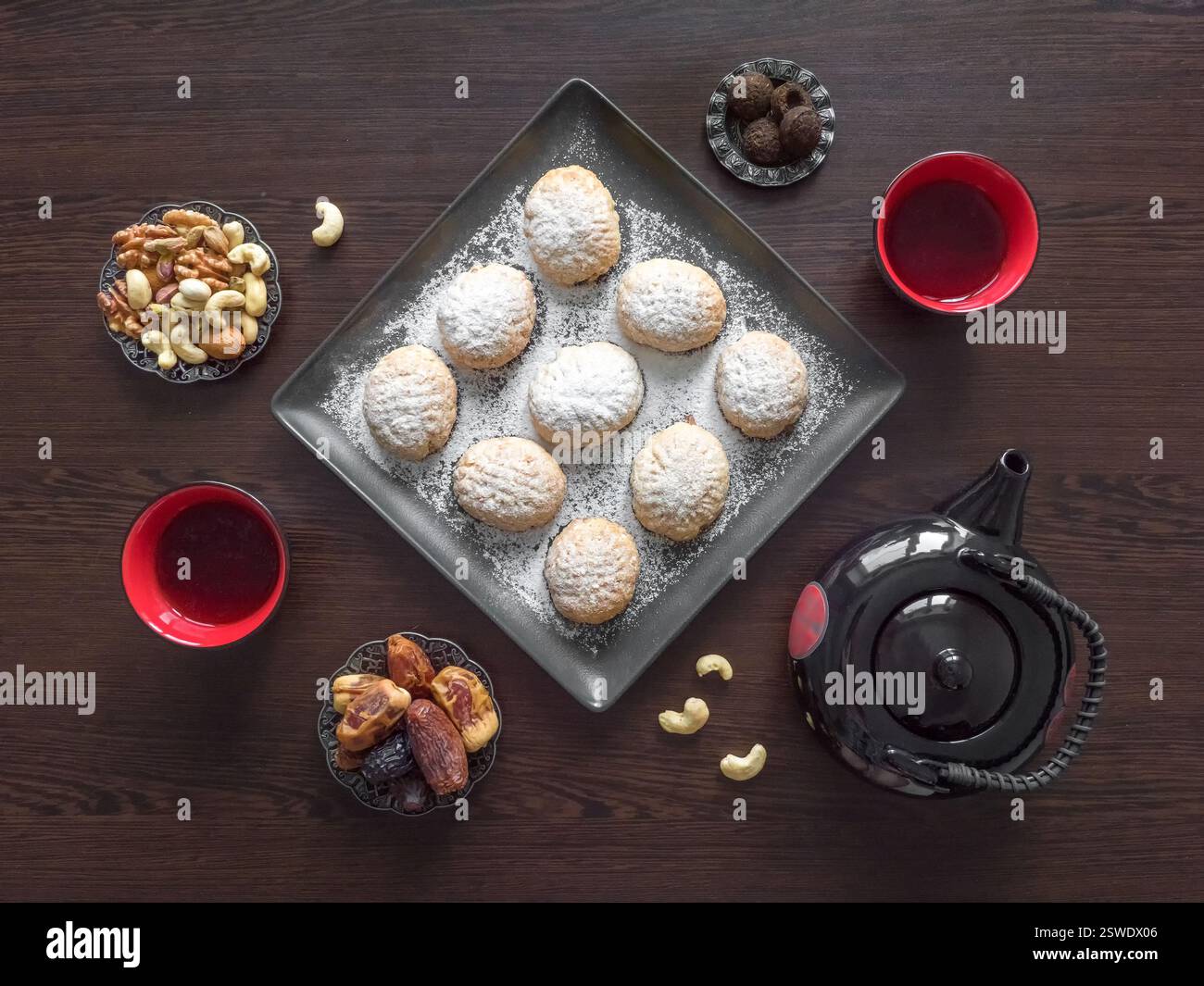 Handmade Ramadan sweets are served with tea on the dark wooden table ...