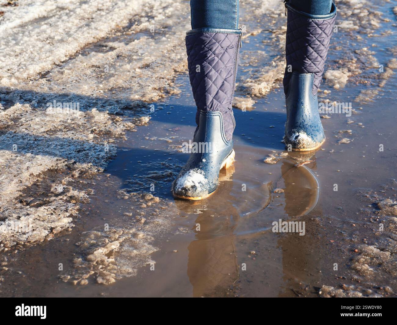The ice melts in the spring, a woman walks through puddles on the ...