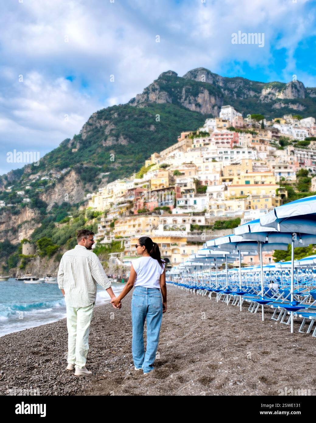 Couple strolls hand in hand along the sandy shores of Positano o Stock ...