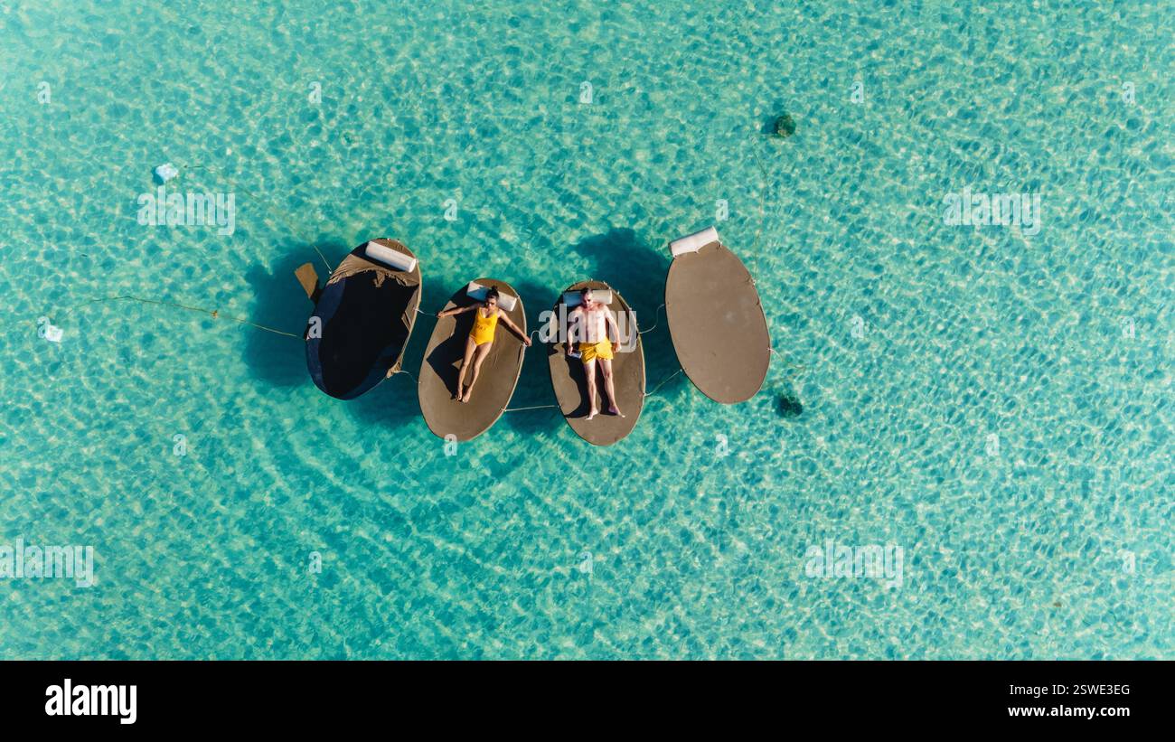 people bask in the warm sun on floating platforms in the crystal-clear ...