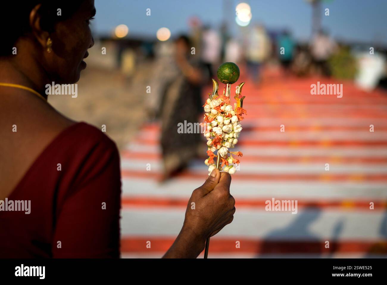 A devotee holds a trident, a symbol of Hindu god Shiva, as she climbs ...