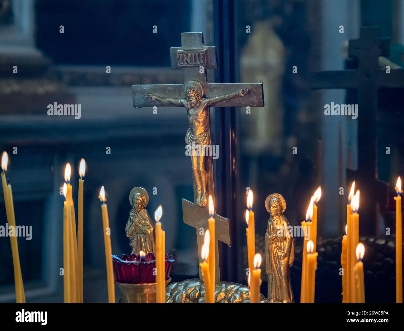 Selective focus. Church candles burn in front of a statuette of the ...