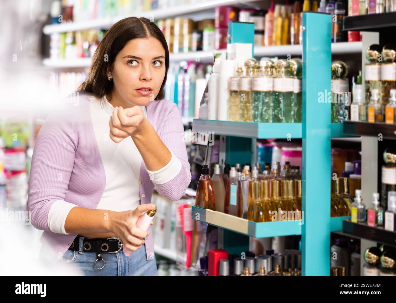 Stylish woman smelling perfume tester, choosing perfume in cosmetic ...
