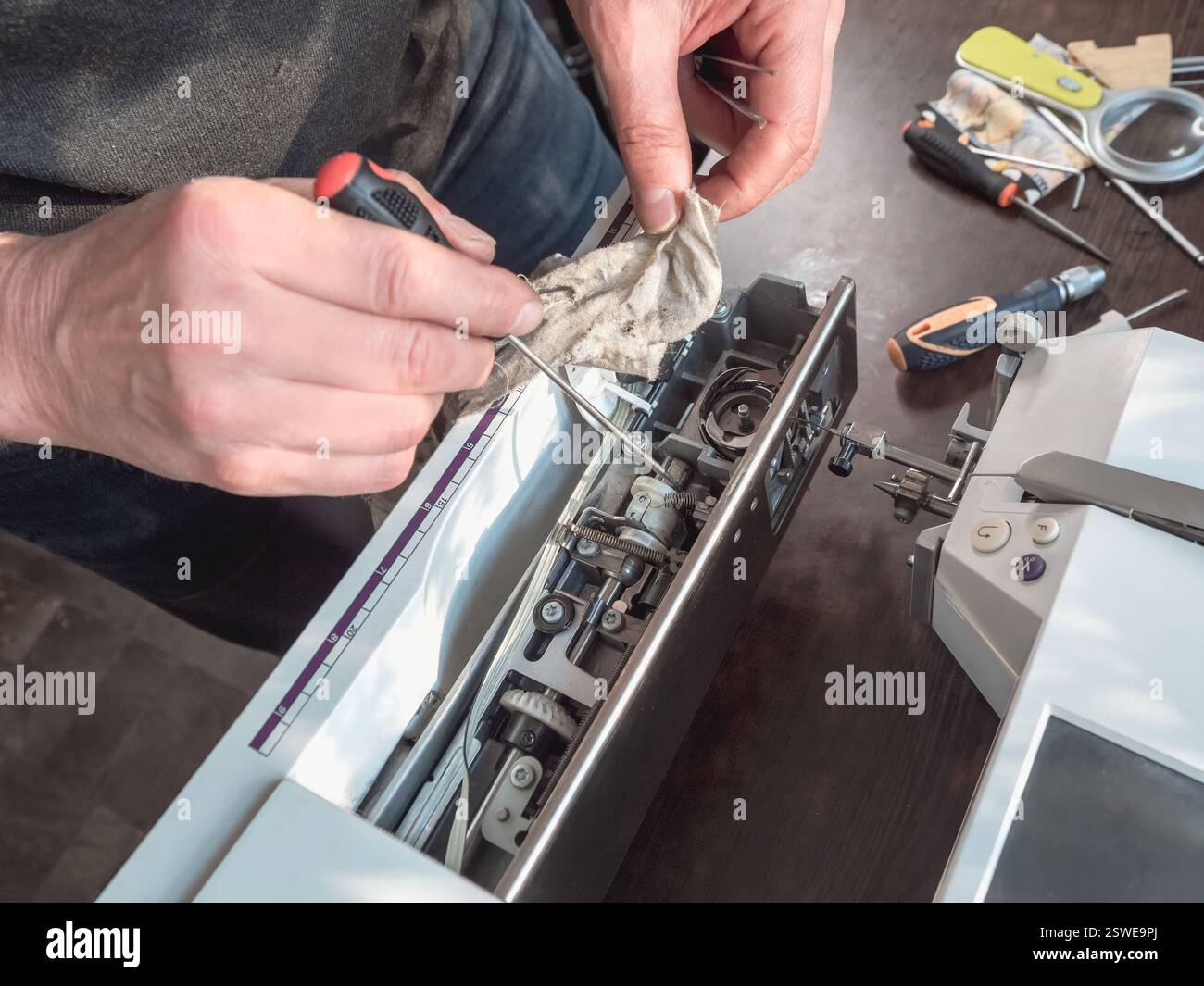 Male master repairs the sewing machine. Internal cleaning of the Stock ...