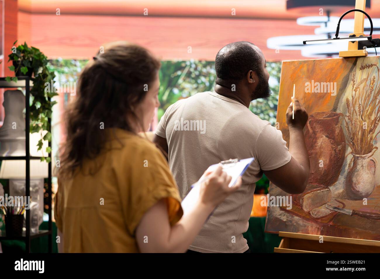 Woman master painter teaching her apprentice to use new painting ...