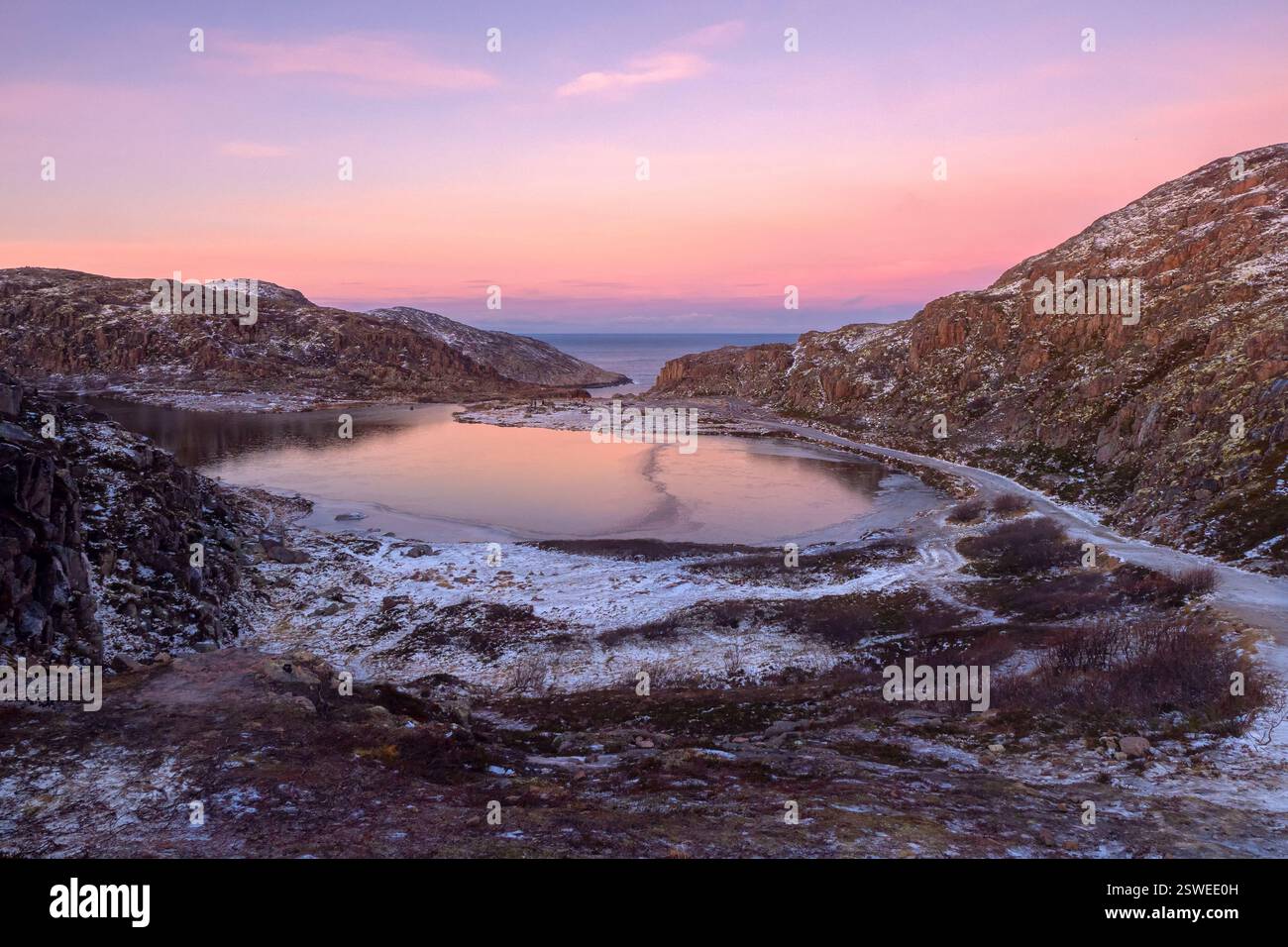 Frozen mountain lake in the gorge. A narrow path leads around the lake ...