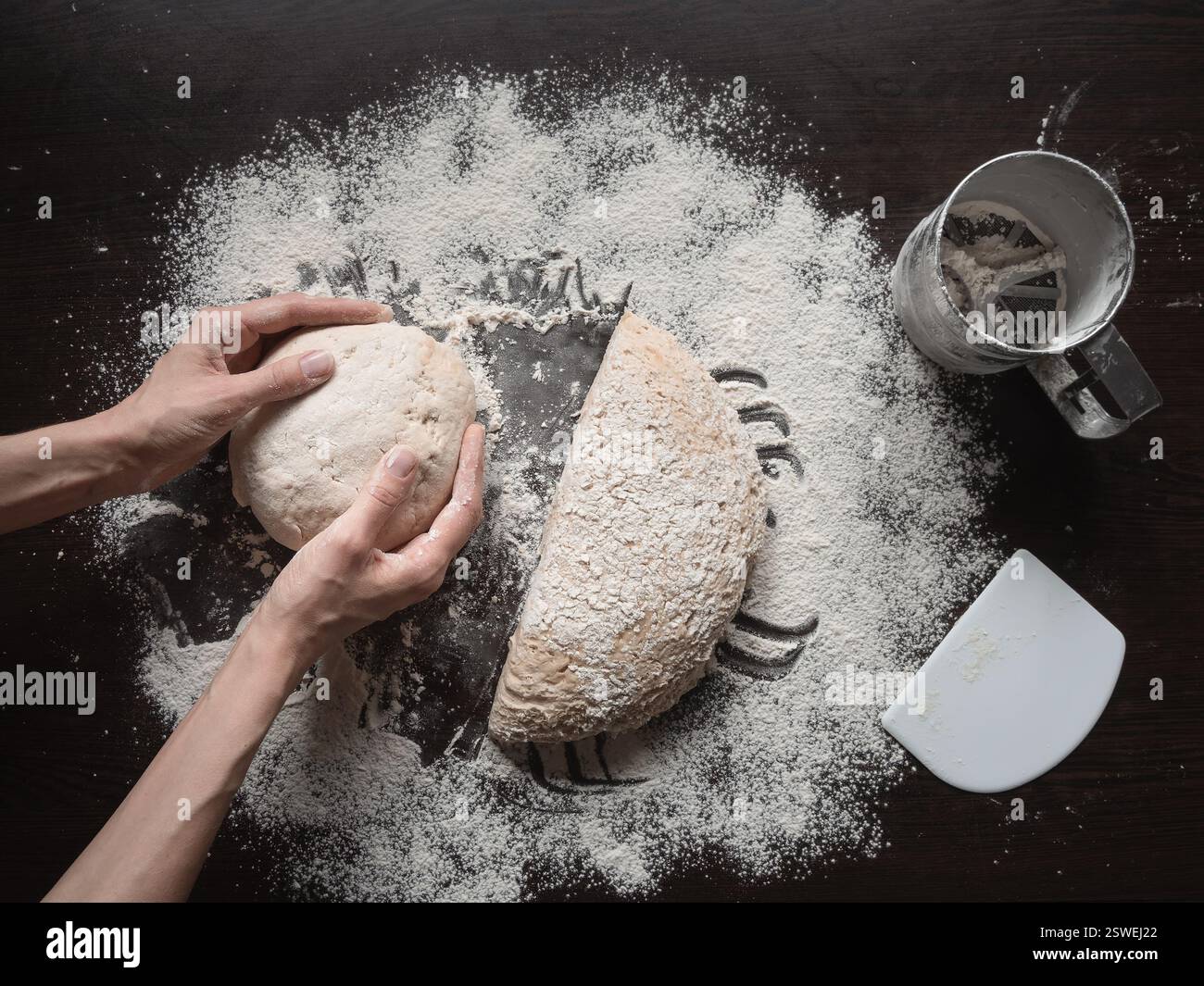 Baker's hand holds the raw yeast-free dough on a dark background. White ...