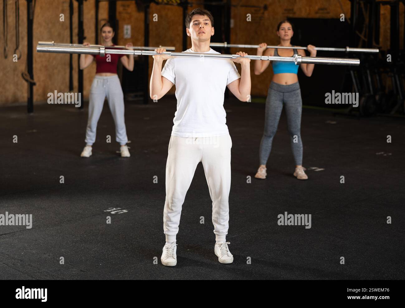Slender guy trains muscles of arms and back using barbell and ...