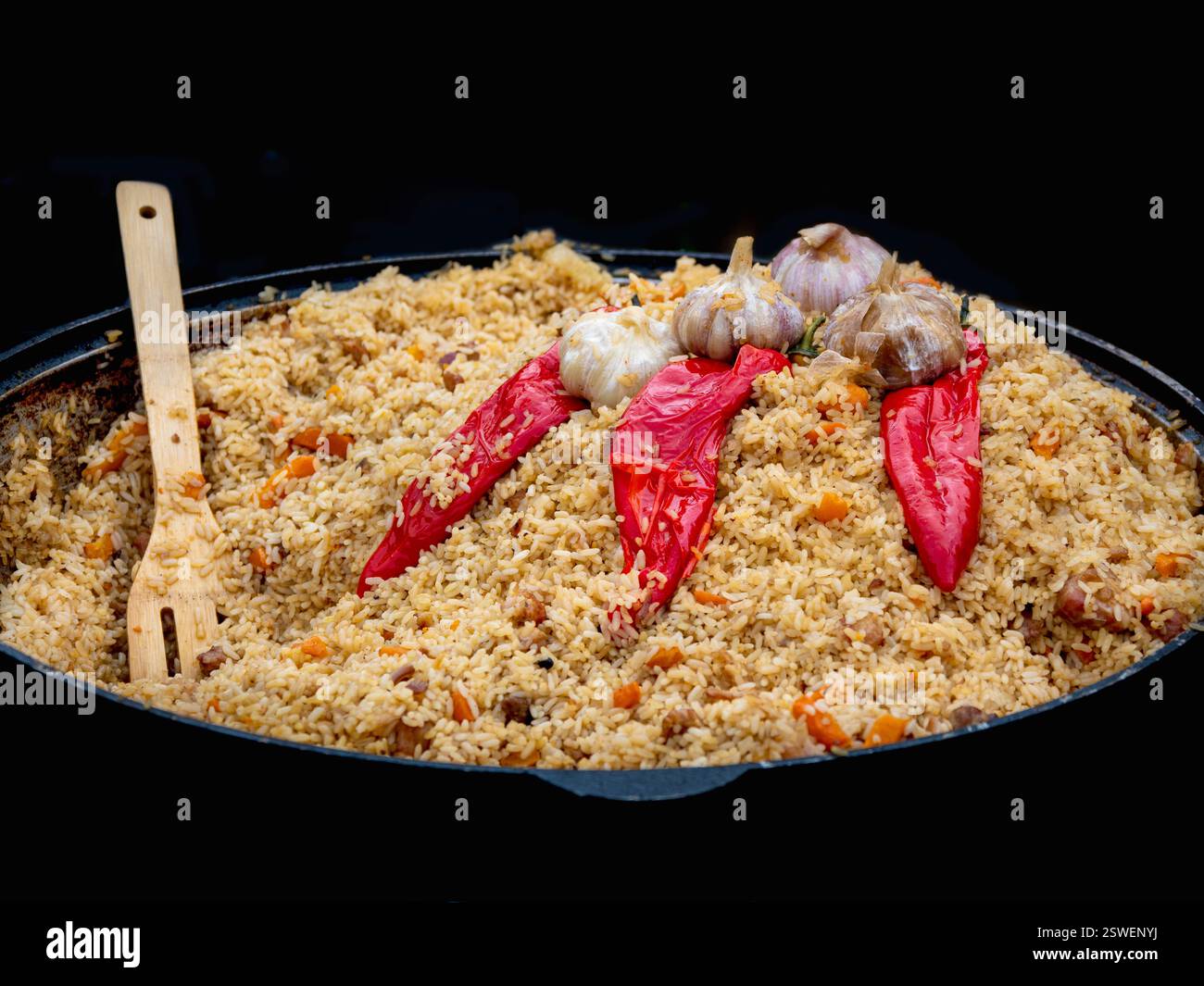 Large cauldron with pilaf on a black background. Street food concept ...
