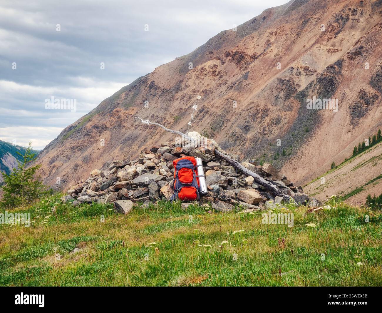 Large orange backpack on a pile of stones of an Alpine slope. Hiking in ...